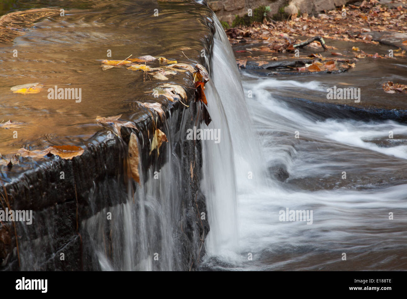 Water spilling over a small dam, with Fall leaves surrounding it Stock ...