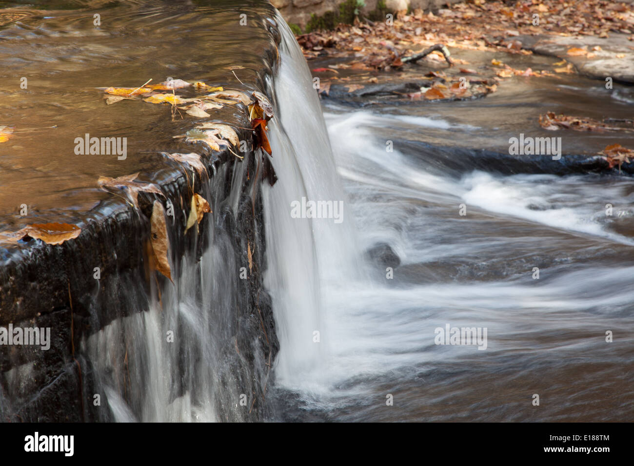 Water spilling over a small dam, with Fall leaves surrounding it Stock ...