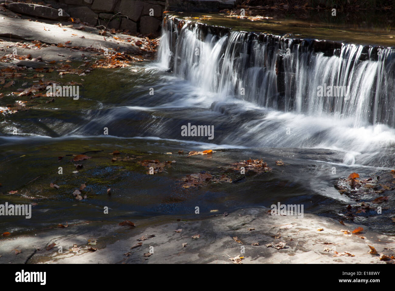 Water flowing over a small dam in the fall of the year Stock Photo - Alamy