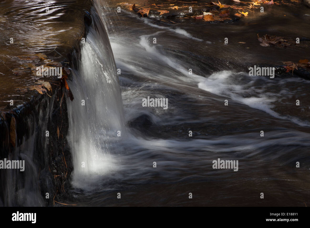 Water flowing over a small dam in the fall of the year Stock Photo - Alamy