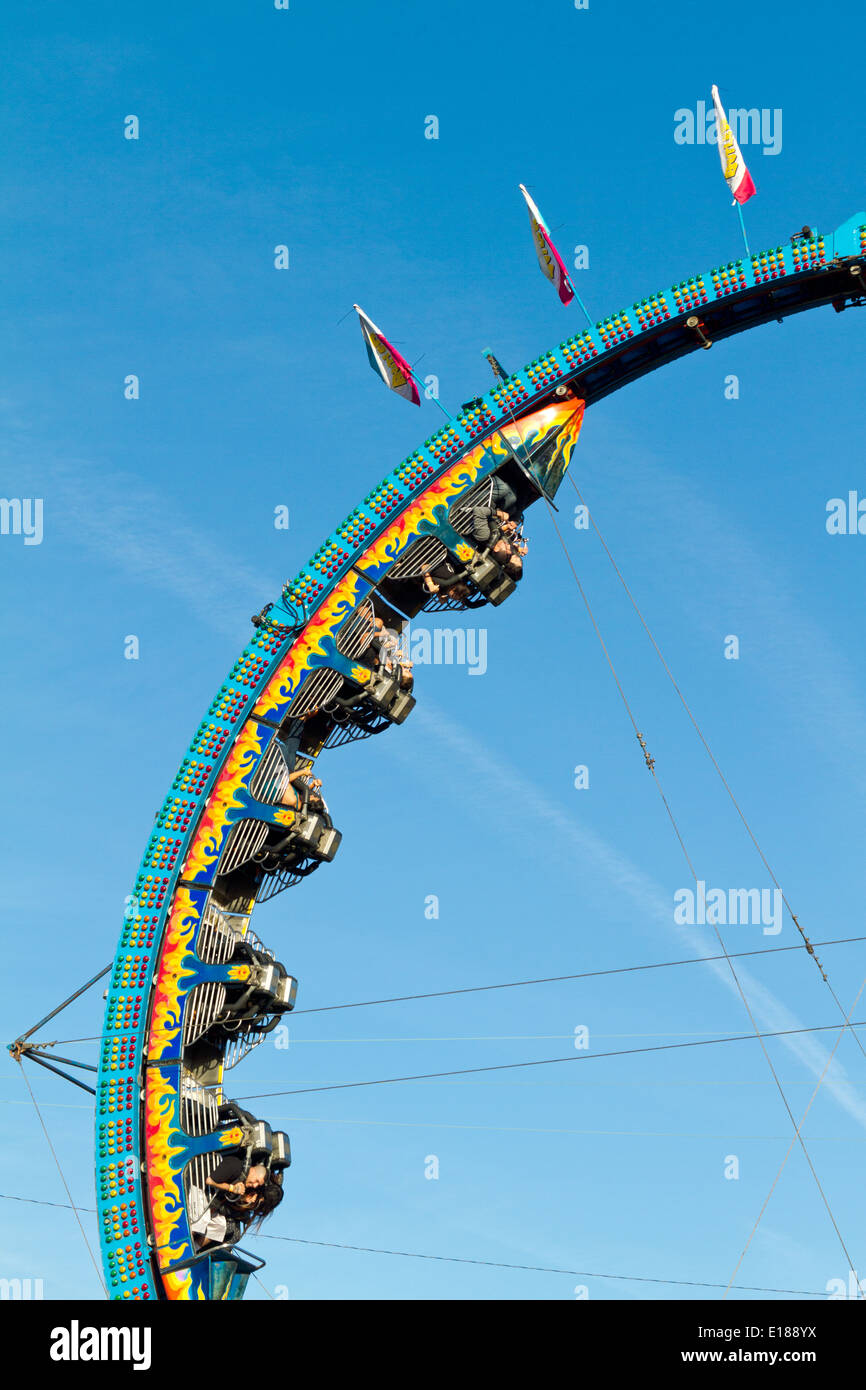 Excited riders hanging upside down on a carnival ride making a loop ...