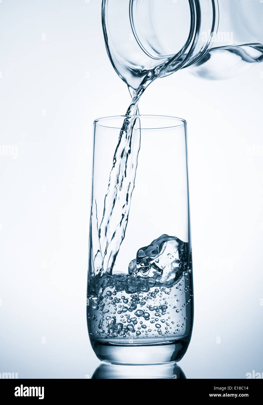 Pouring water from glass pitcher on blue background Stock Photo - Alamy