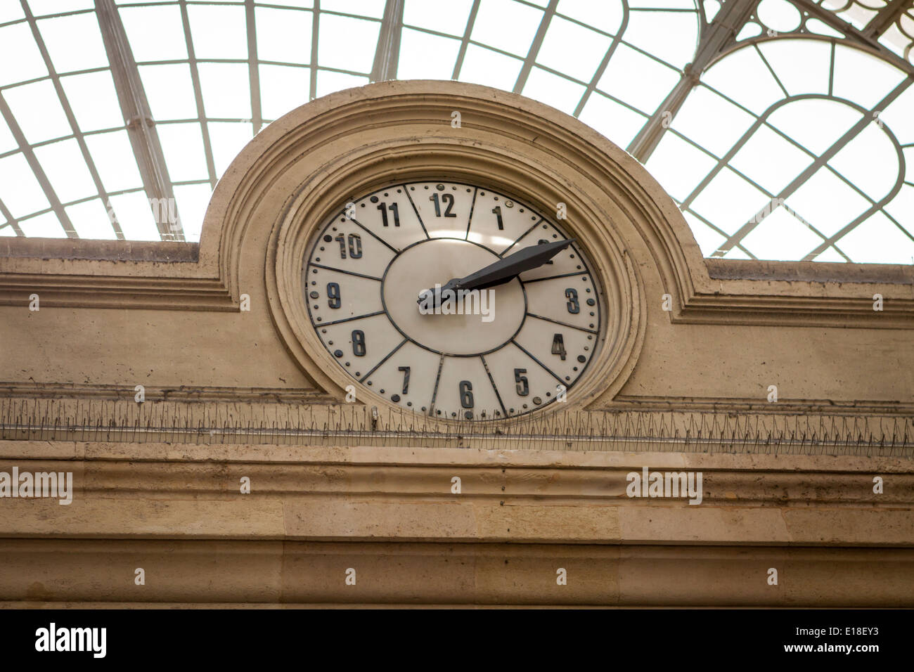 Circular clock inset into a stone building facade under a domed glass ...