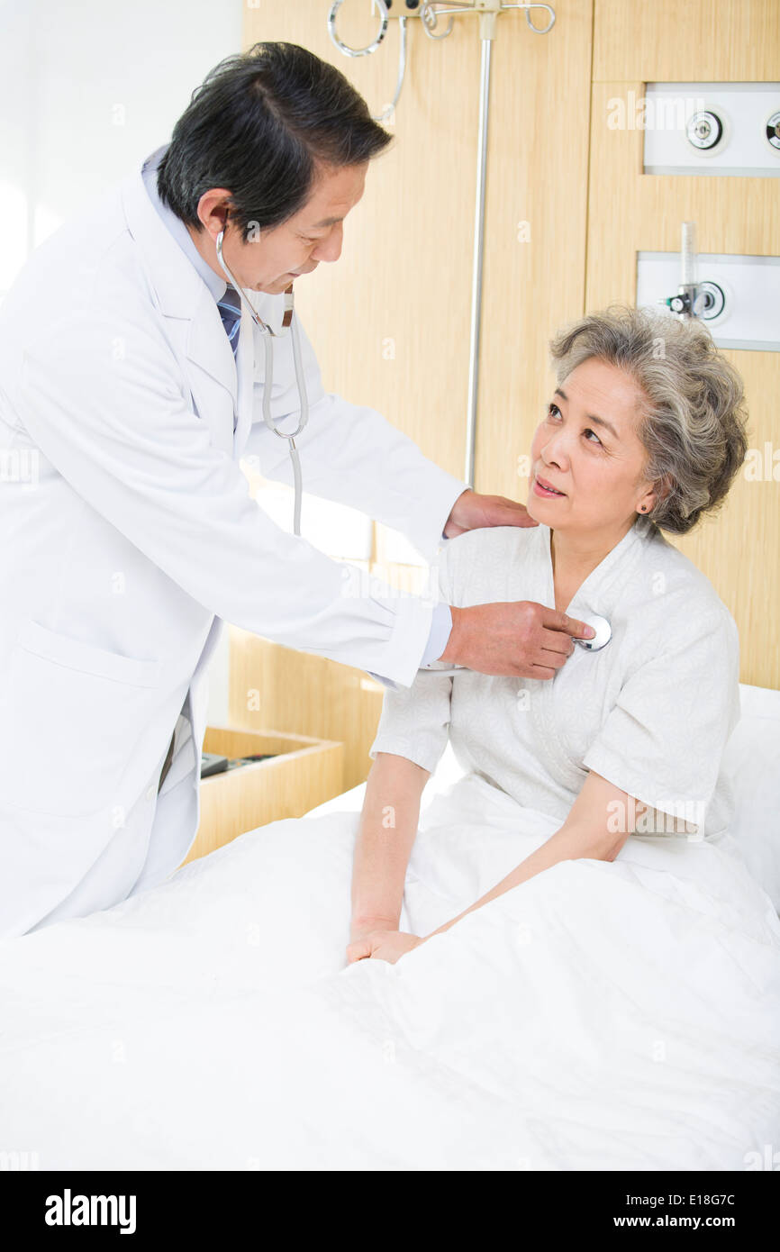 Doctor using stethoscope on patient in hospital Stock Photo - Alamy