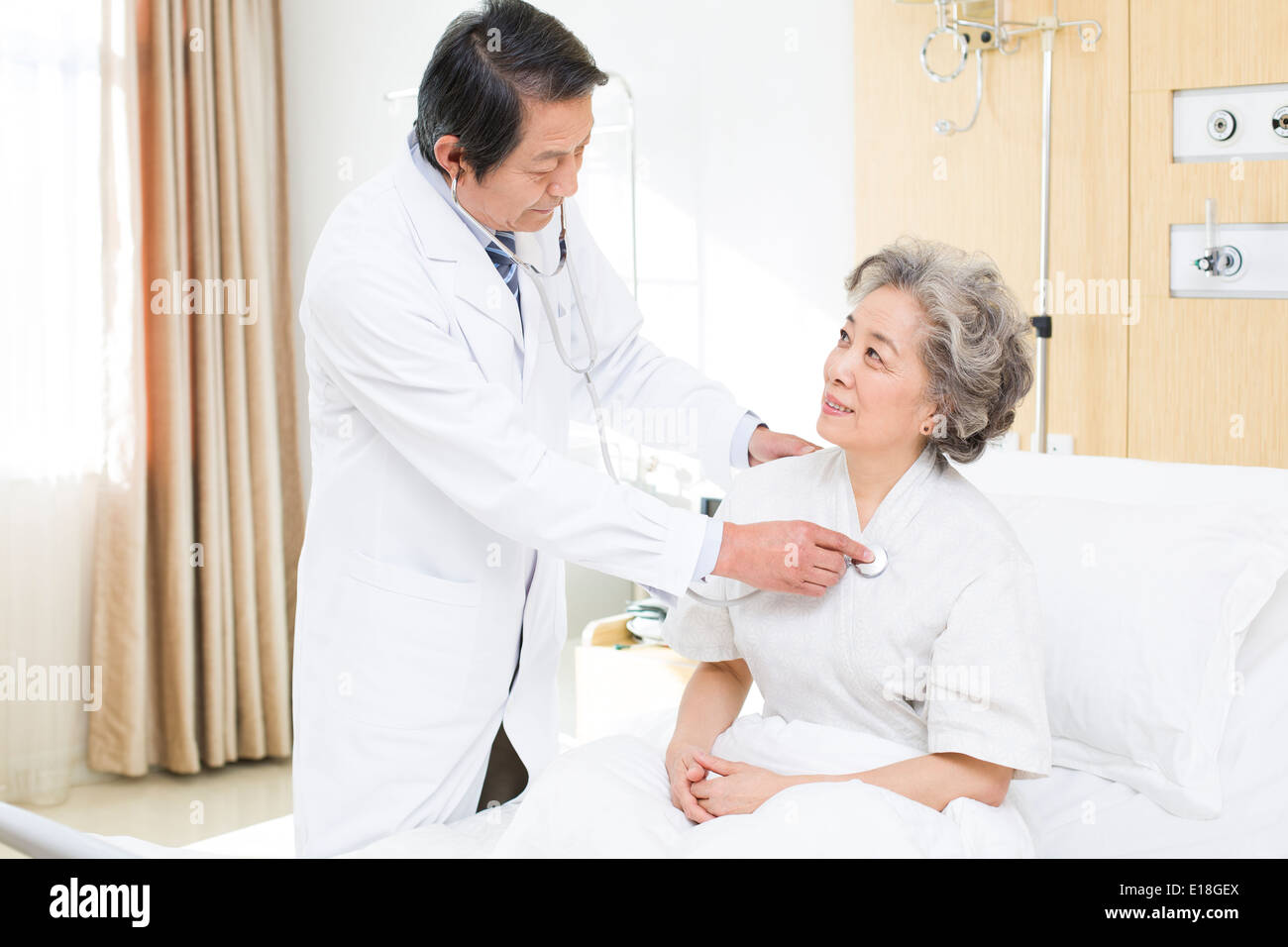 Doctor using stethoscope on patient in hospital Stock Photo - Alamy