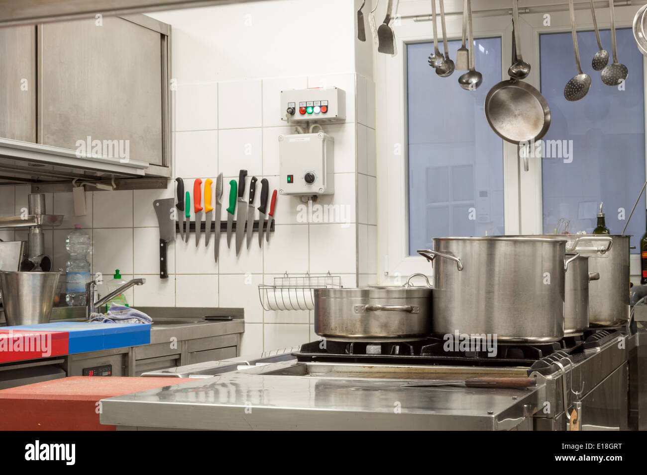 Neat interior of a commercial kitchen with wall mounted utensils and a ...