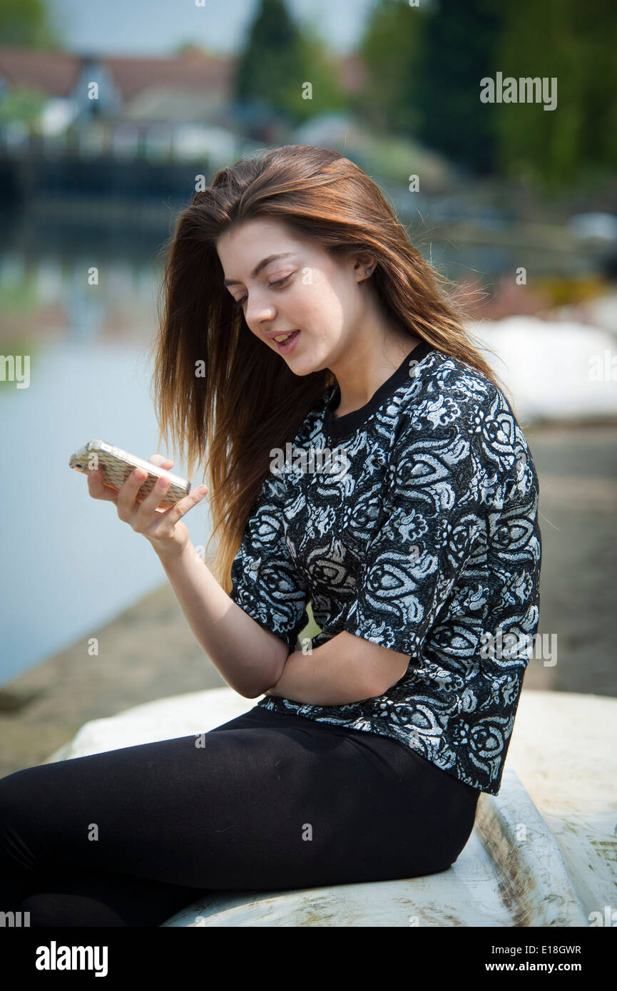 Teenage girl texting a friend while sitting outside Stock Photo - Alamy