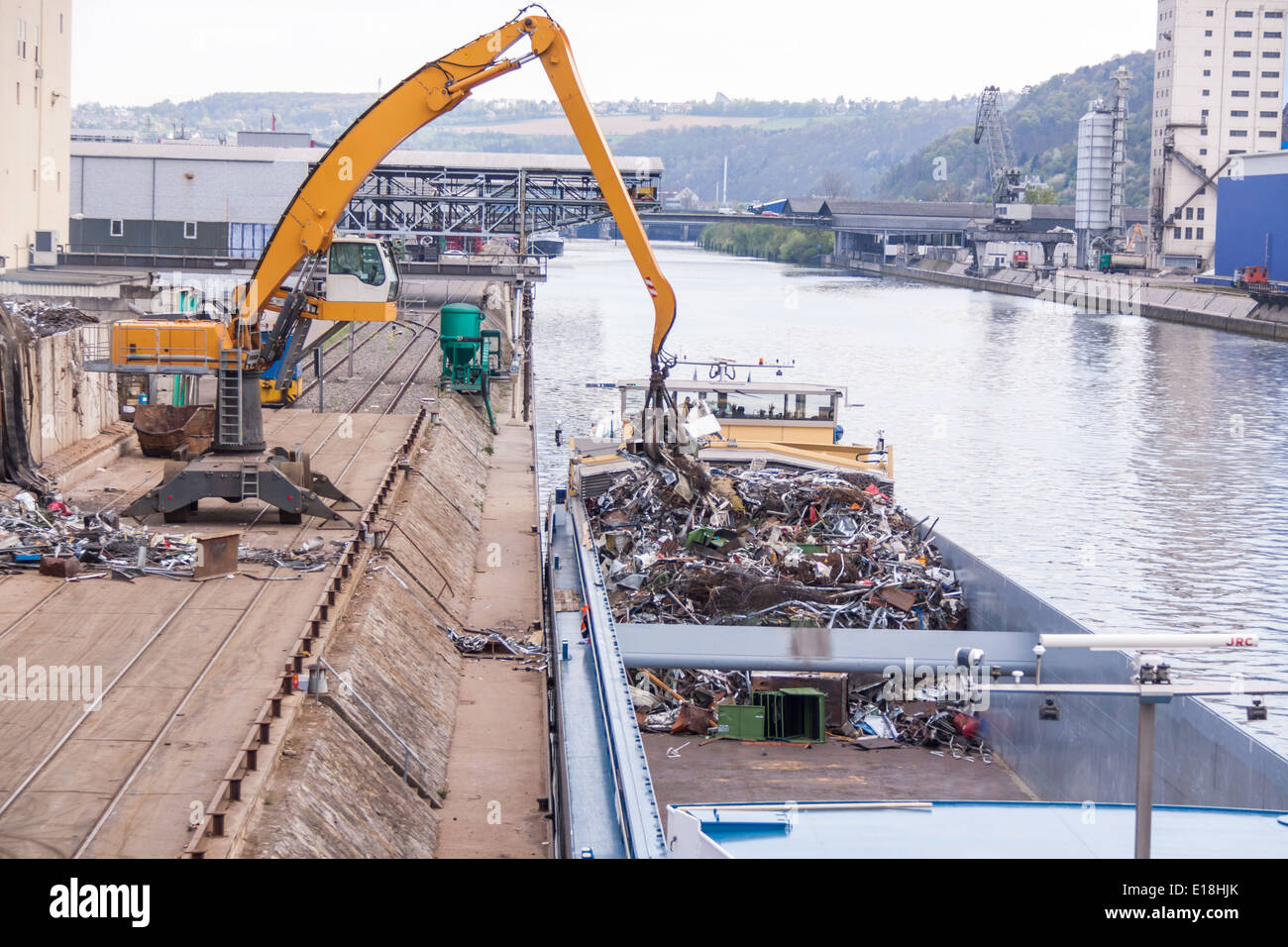 Open barge being loaded or offloaded at a wharf on an urban waterway or ...