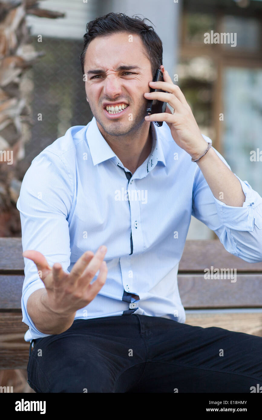 Man sitting on bench screaming on phone Stock Photo - Alamy