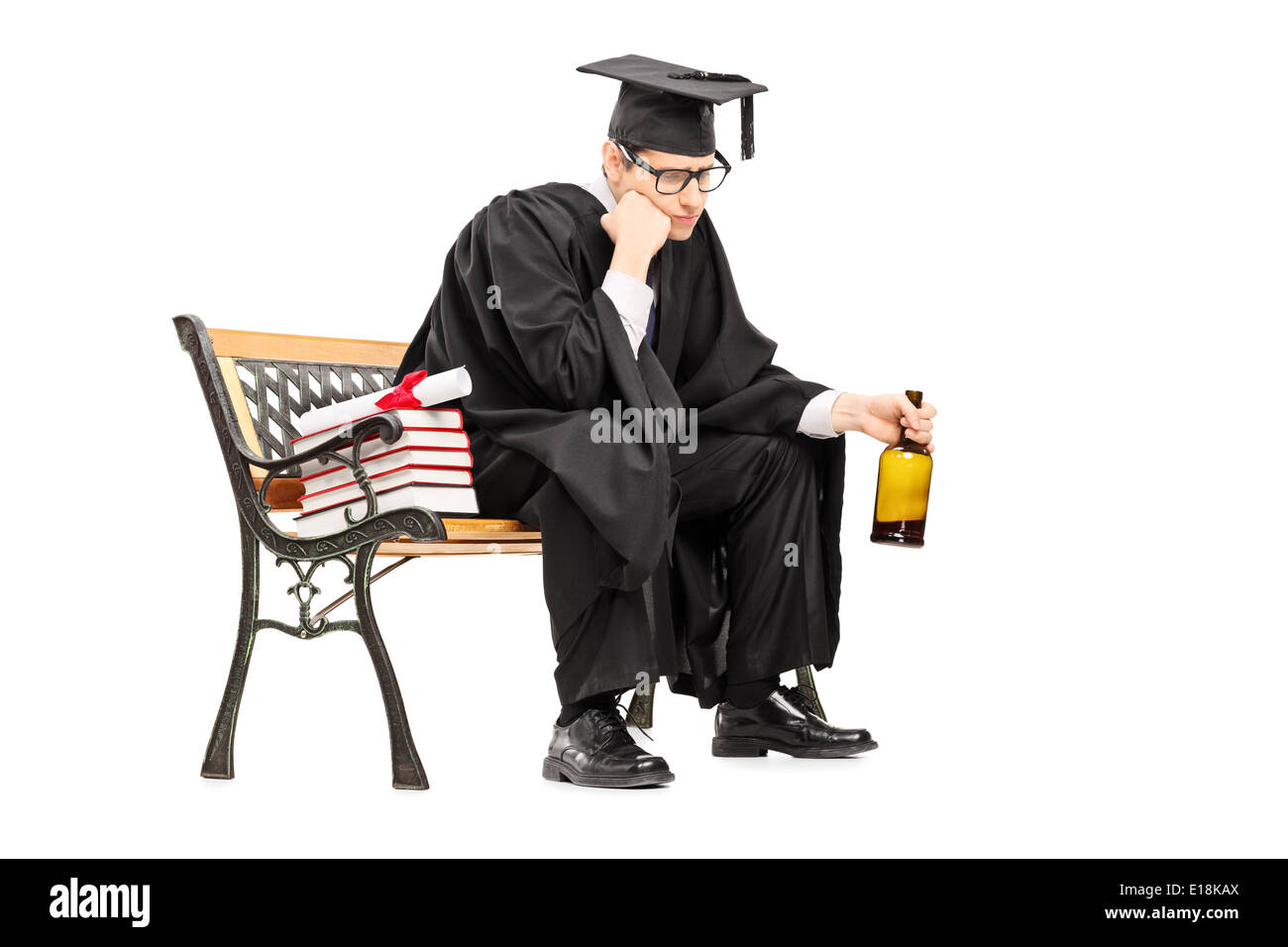 Sad college graduate drinking alcohol seated on bench Stock Photo - Alamy