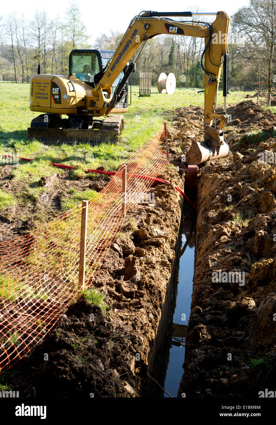 digger in a field with trench for underground electricity cable Stock ...