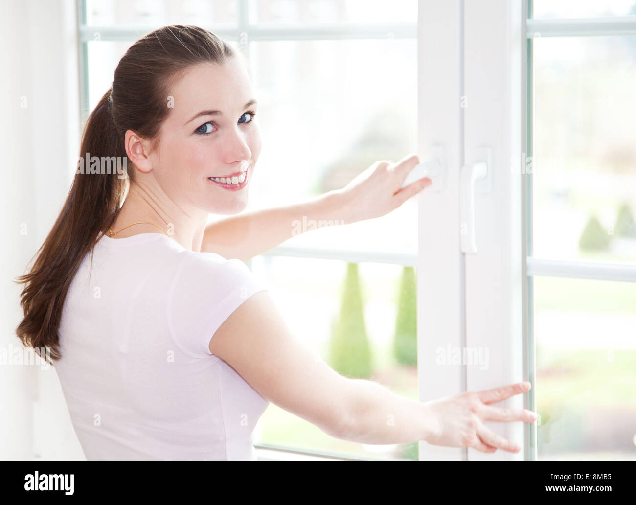 Attractive young woman closes window Stock Photo - Alamy