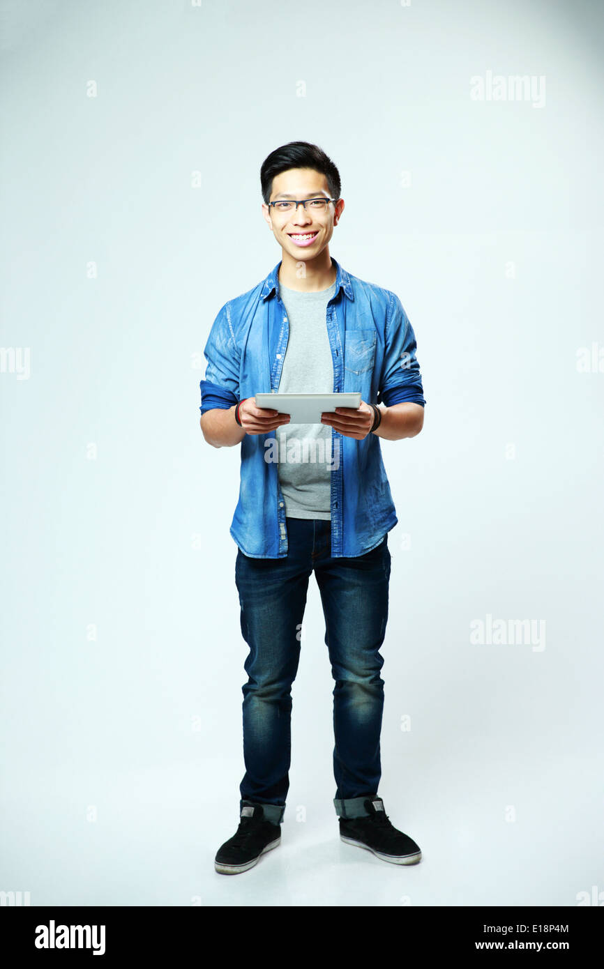 Full length portrait of a young smiling man standing with laptop on ...