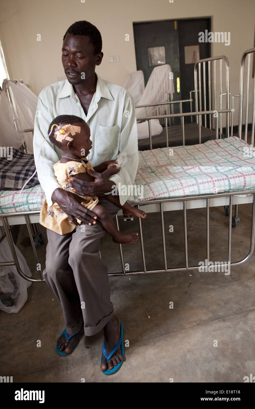 A man sits with his daughter suffering from malaria at Amuria Health ...