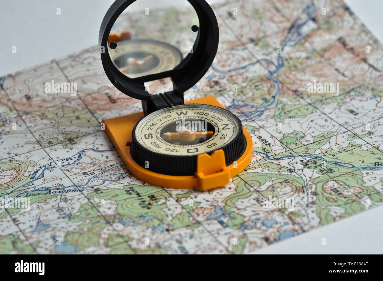 Outdoor compass in orange body with black lid and a mirror in it is ...