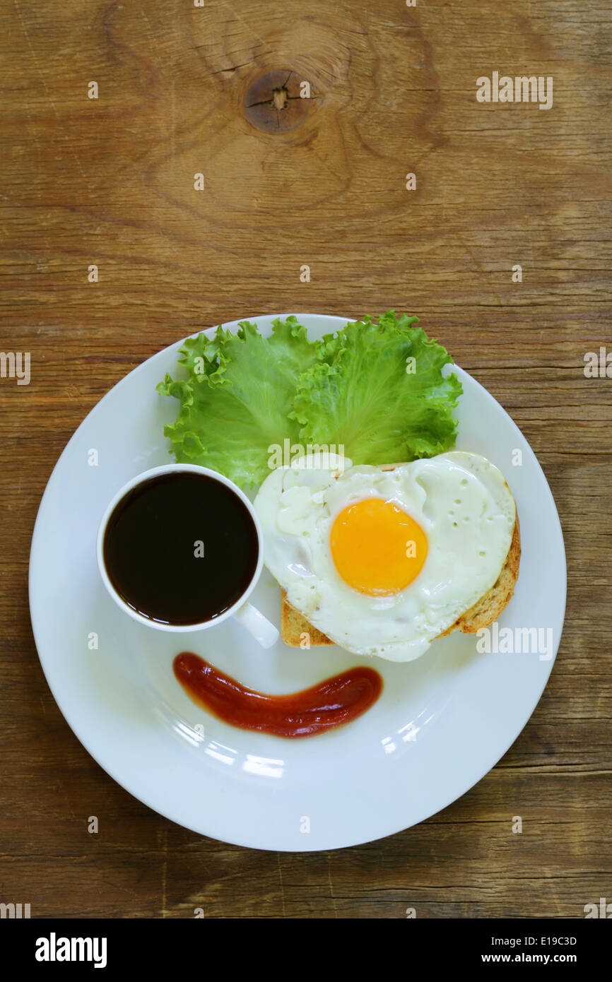 funny face serving breakfast, fried egg, toast and green salad Stock ...