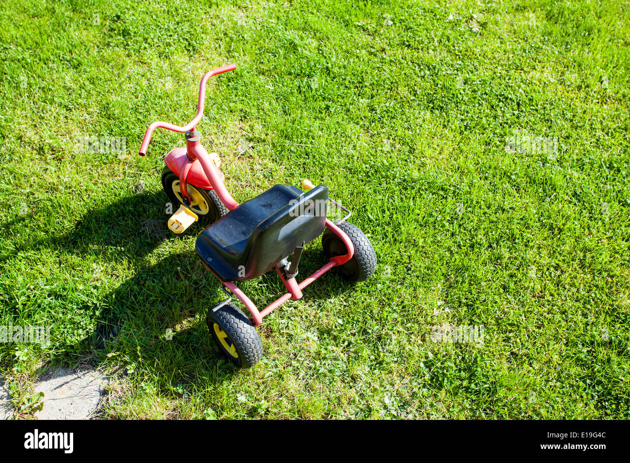 Childhood. Small red tricycle cycle toy on the green grass. Outdoor ...