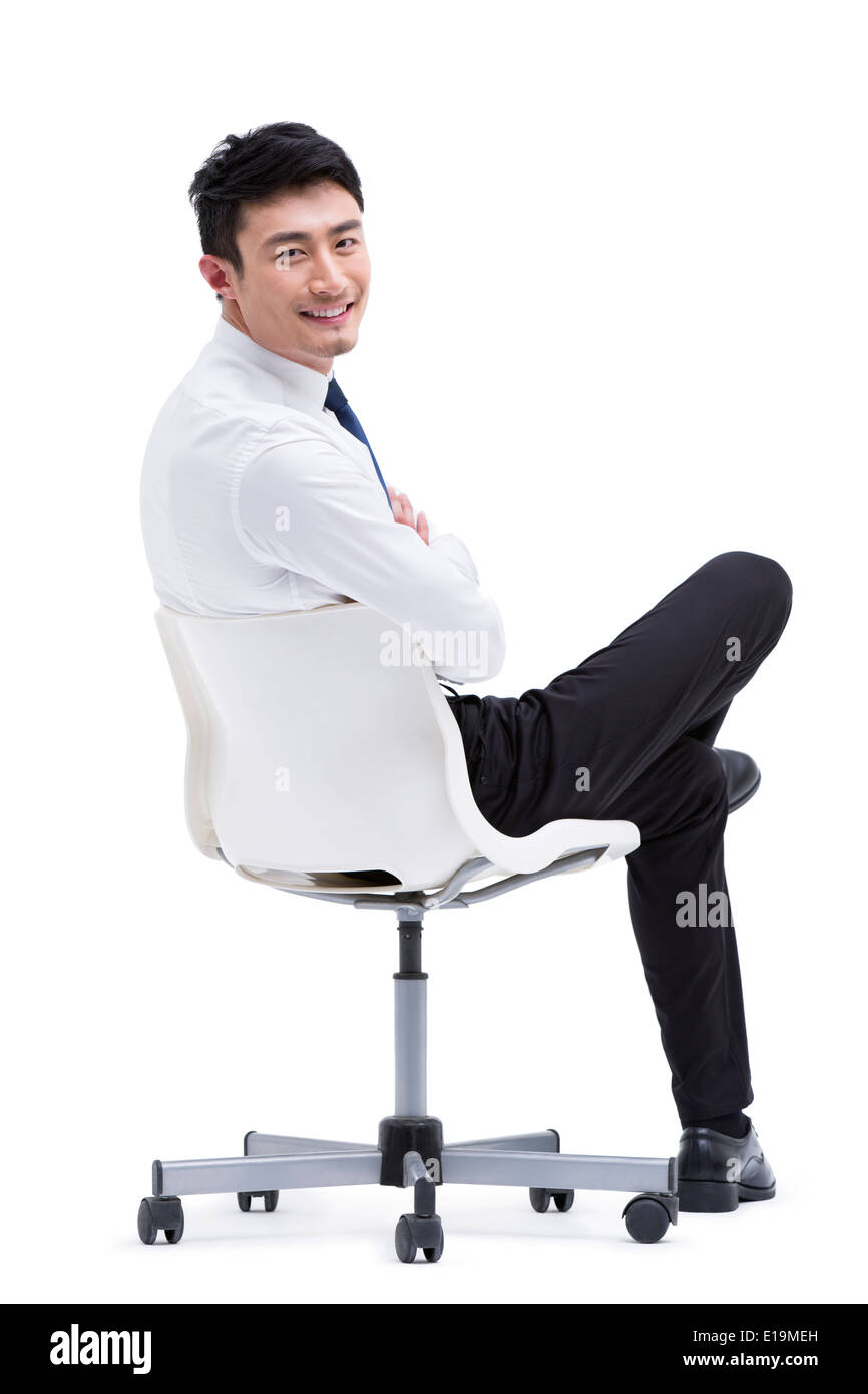 Confident young businessman sitting on chair Stock Photo - Alamy