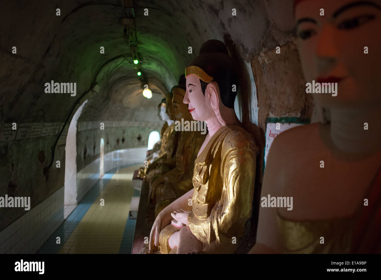 Statues of Buddha line this narrow corridor underneath a huge stupa in ...