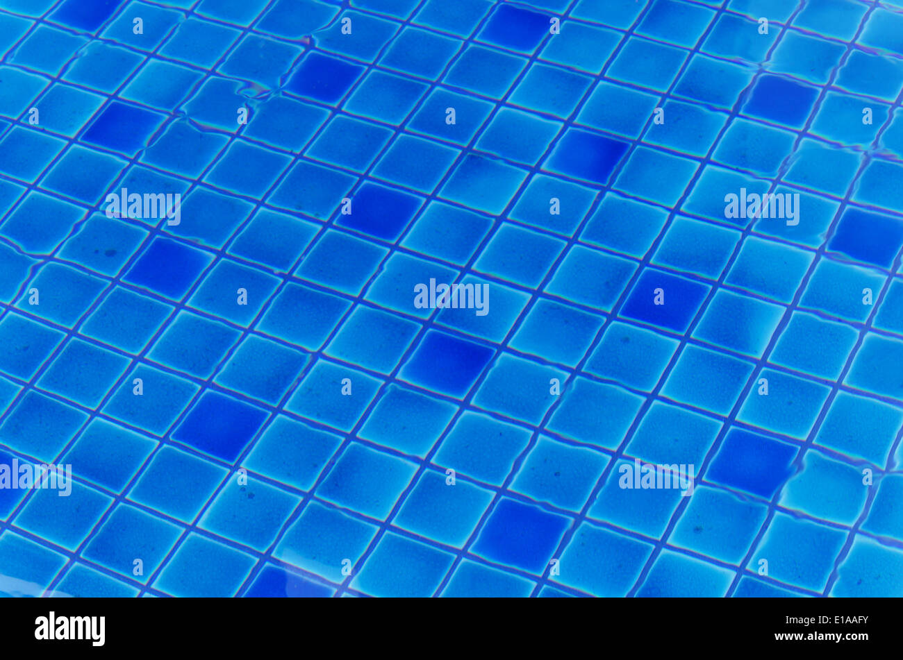 reflection on the blue clear water ripples of swimming pool with mosaic ...