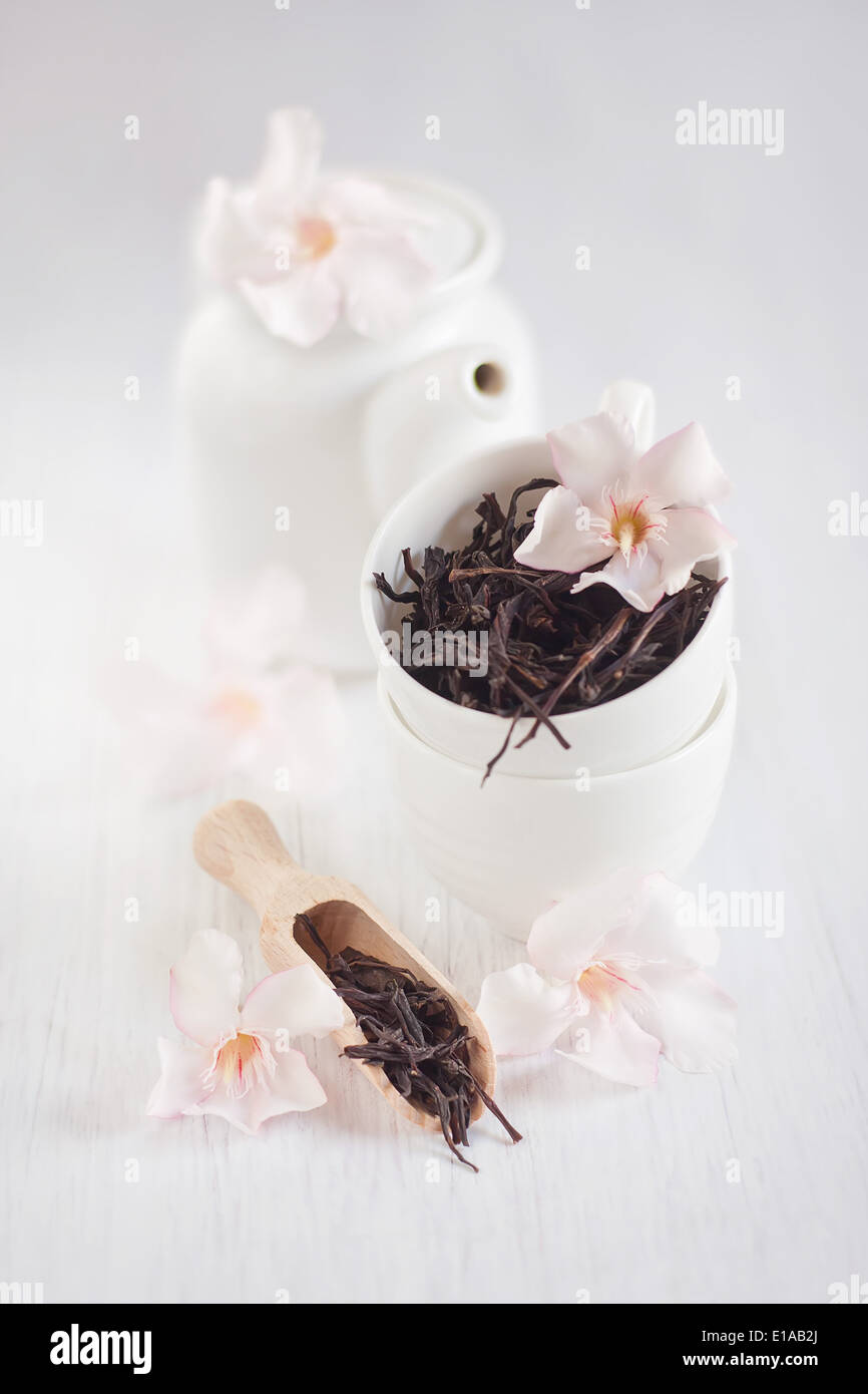 Oolong tea in a scoop, cups and teapot with light rose rhododendron ...