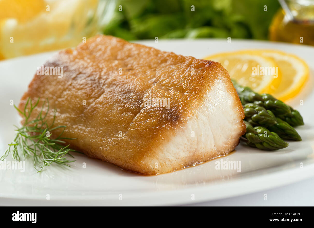 A delicious pan seared white fish with asparagus, salad, lemon, and ...