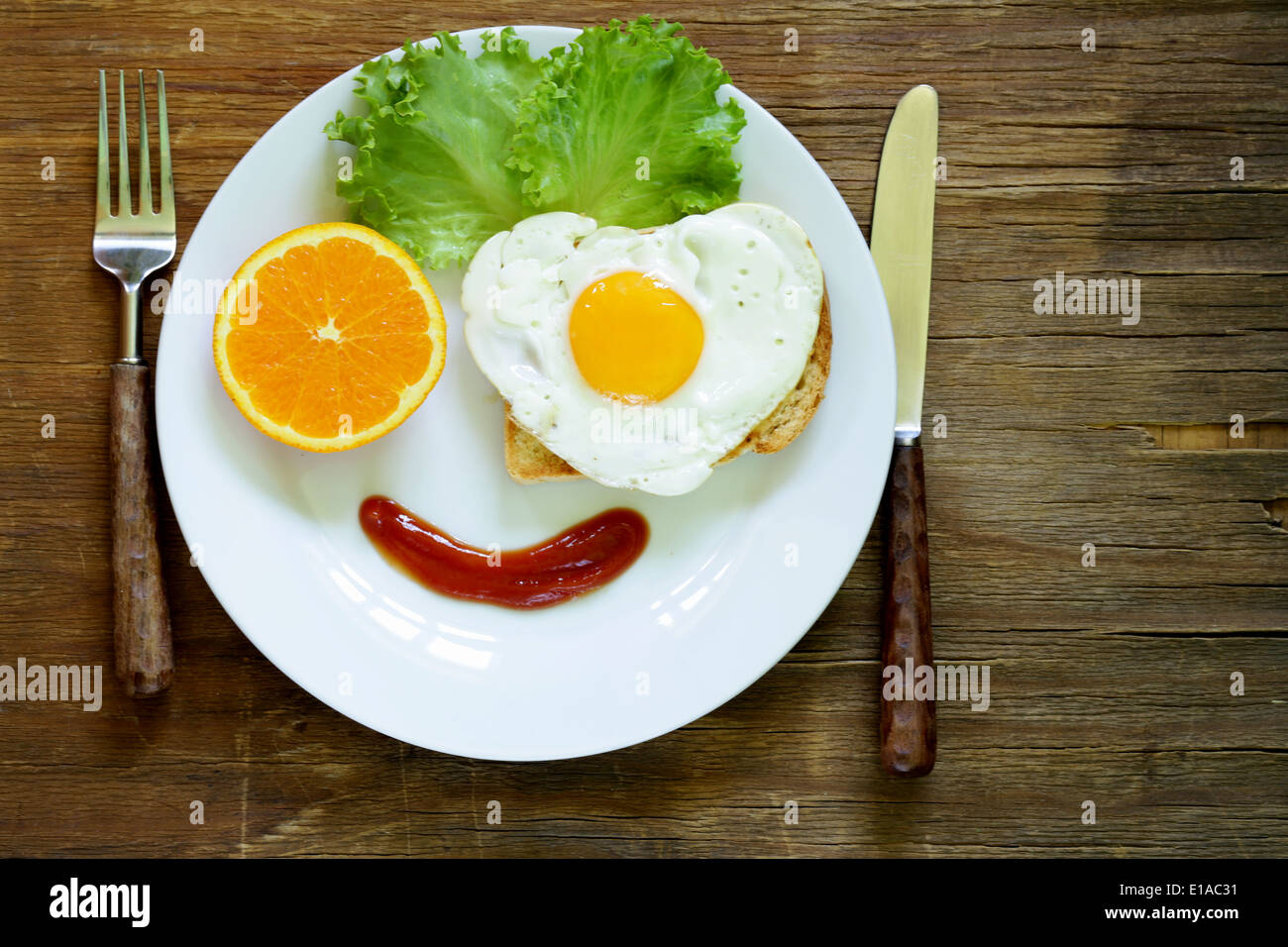 funny face serving breakfast, fried egg, toast and green salad Stock ...