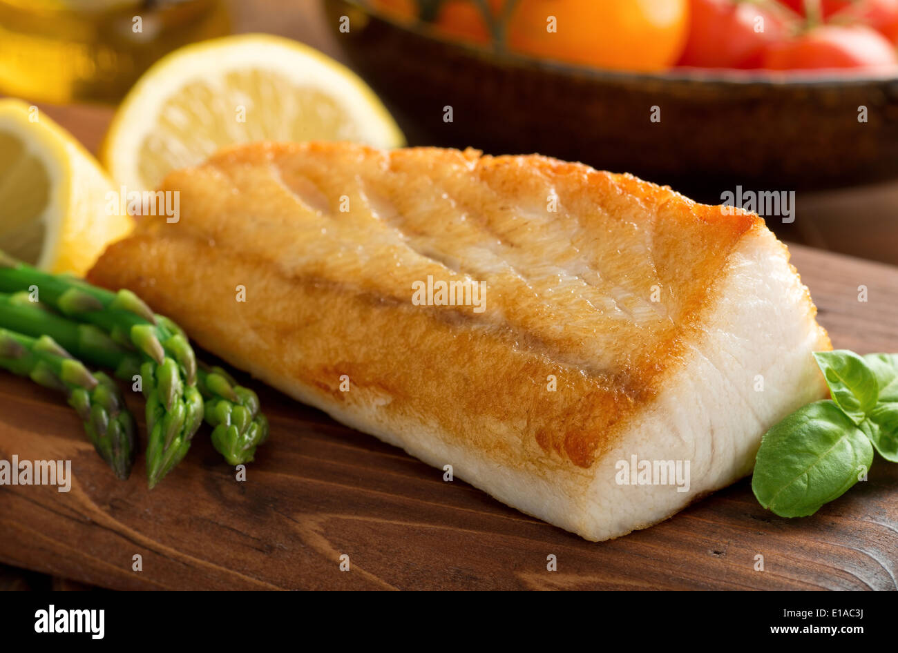 A delicious pan seared white fish with asparagus, salad, and lemon ...