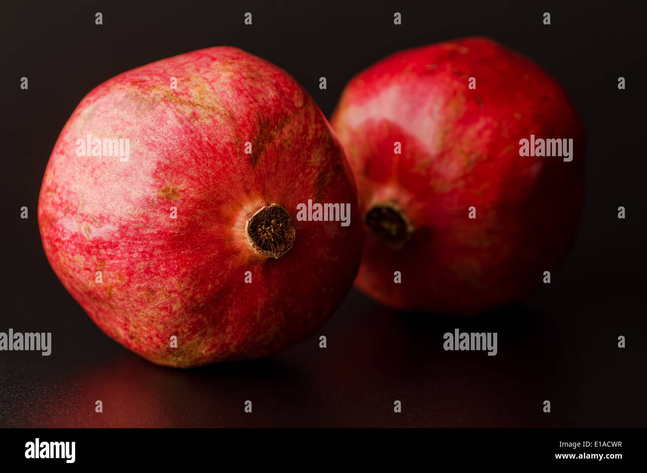 Two pomegranates against a dark background Stock Photo - Alamy