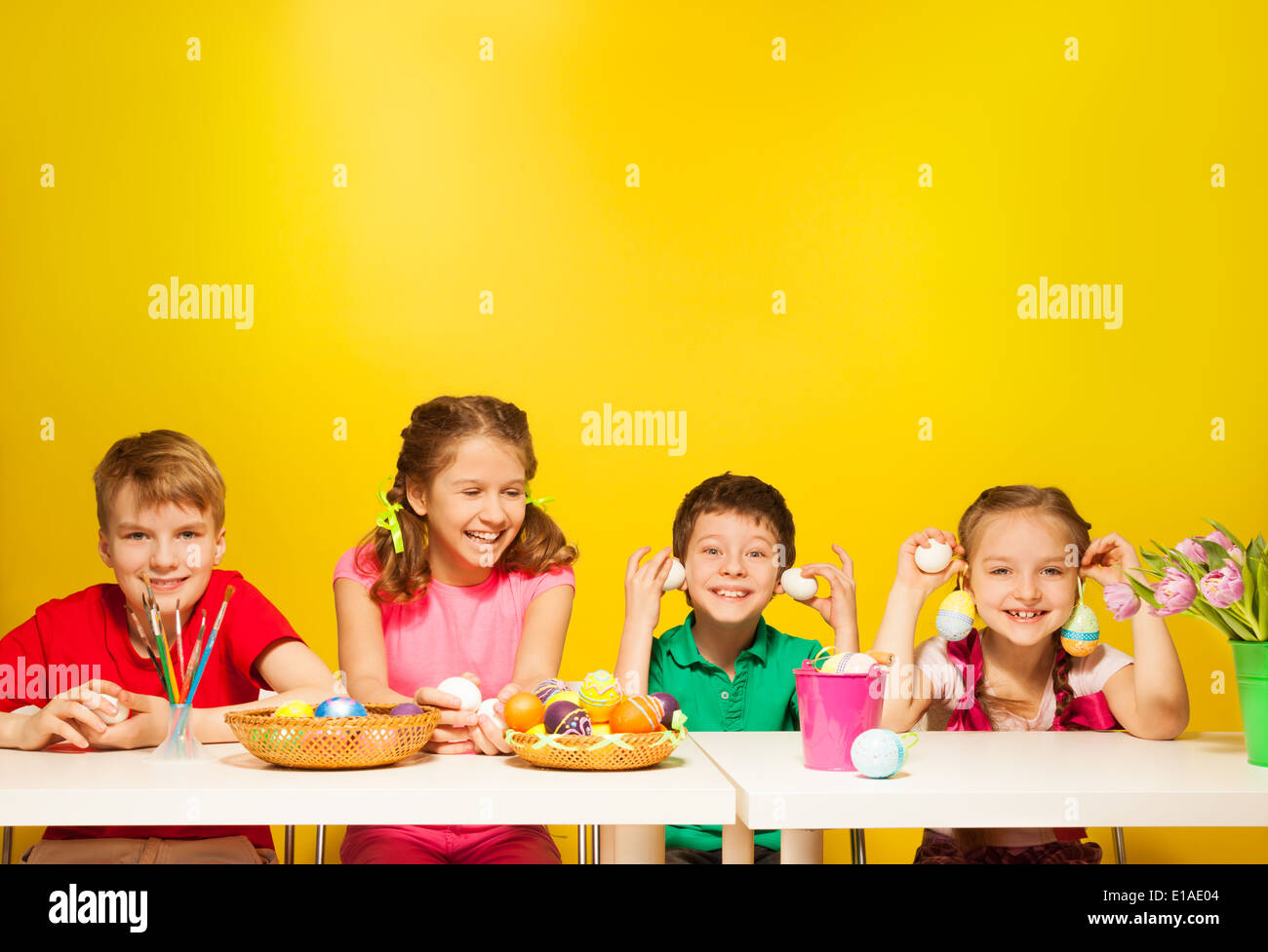 Group of kids sit at the table with Easter eggs Stock Photo - Alamy