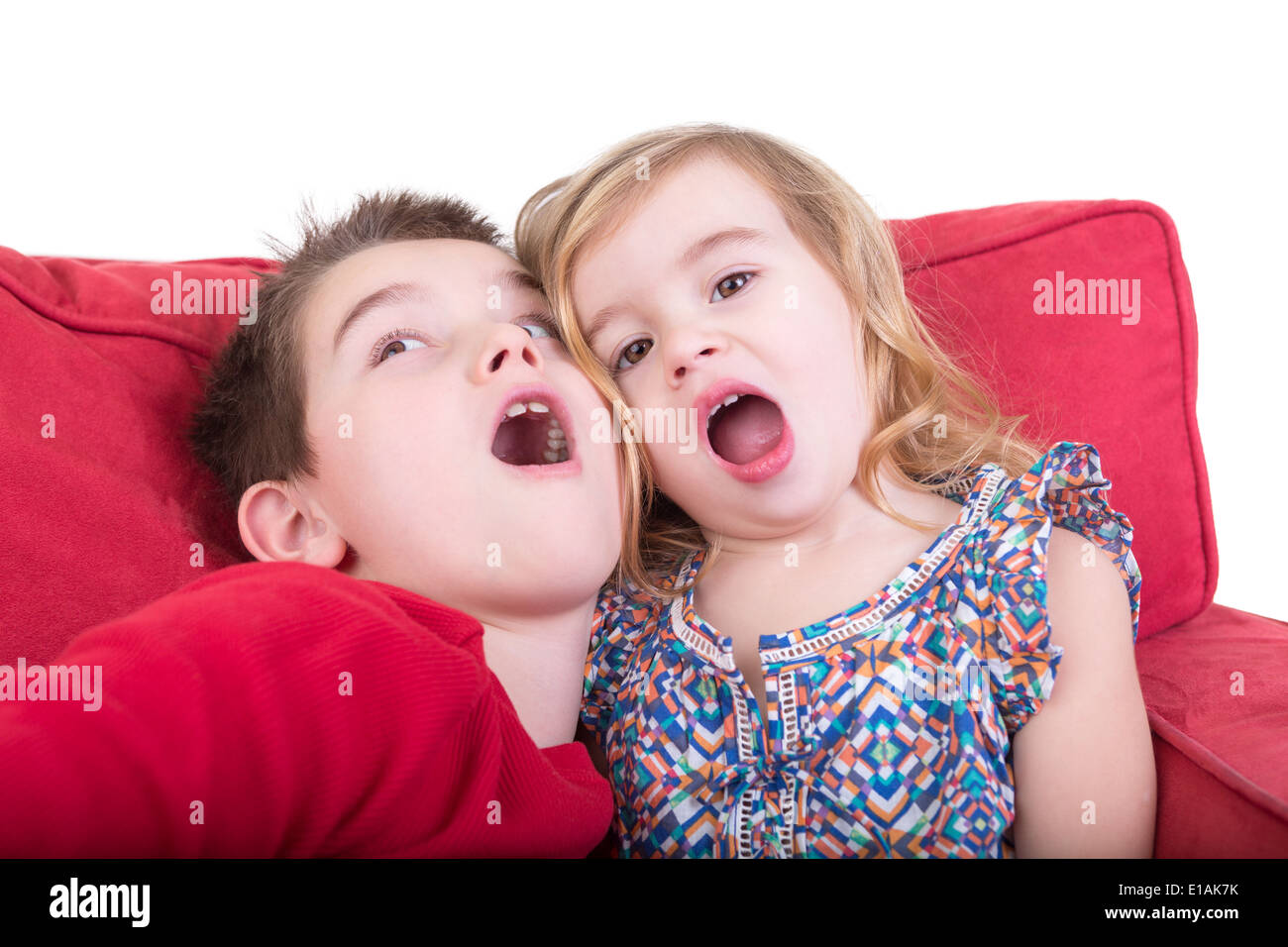 Two playful young children pulling faces as an attractive brother and ...