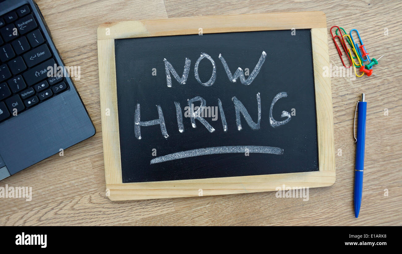Now hiring written on a chalkboard at the office Stock Photo - Alamy