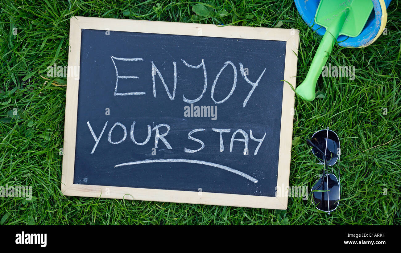 Enjoy your stay written on a chalkboard with sunglasses and child toys ...