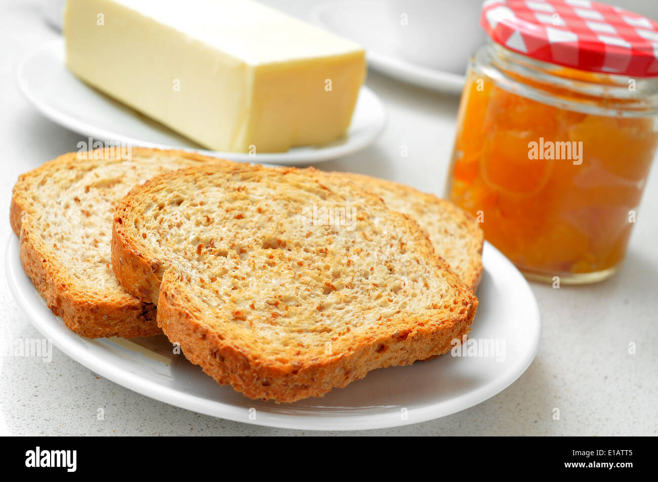 a set table with plates with toasts, butter, a jam jar and a cup of ...