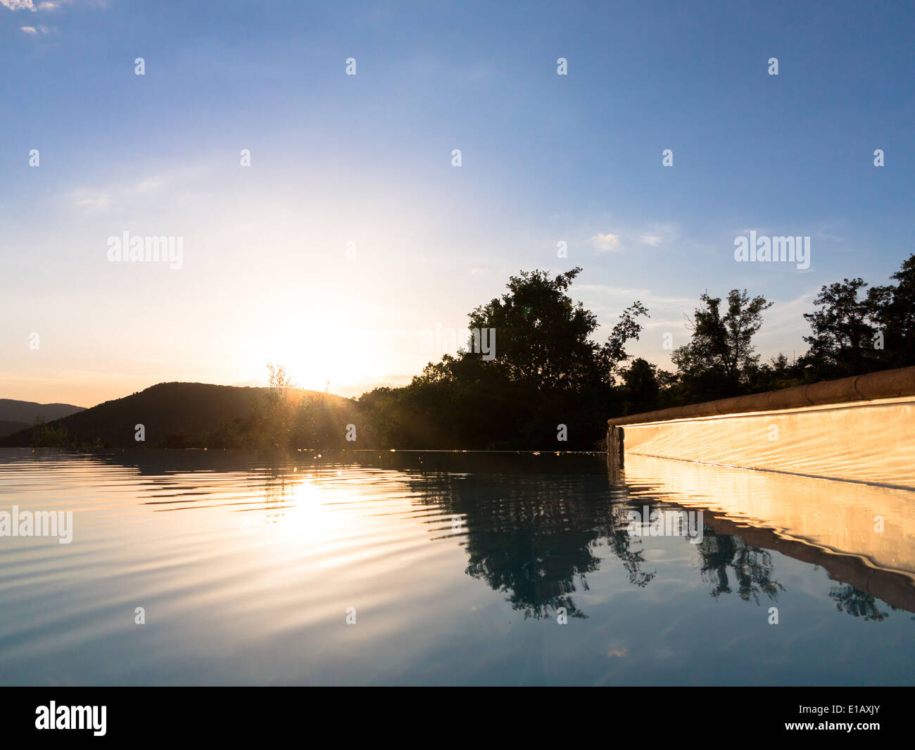 The horizon and reflections in an infinity swimming pool against a dusk ...