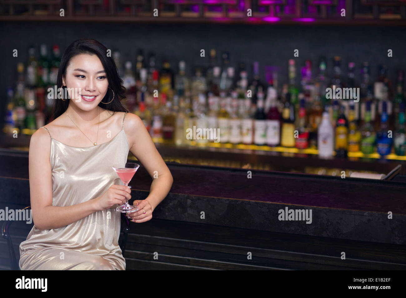 Young woman sitting at bar counter Stock Photo - Alamy