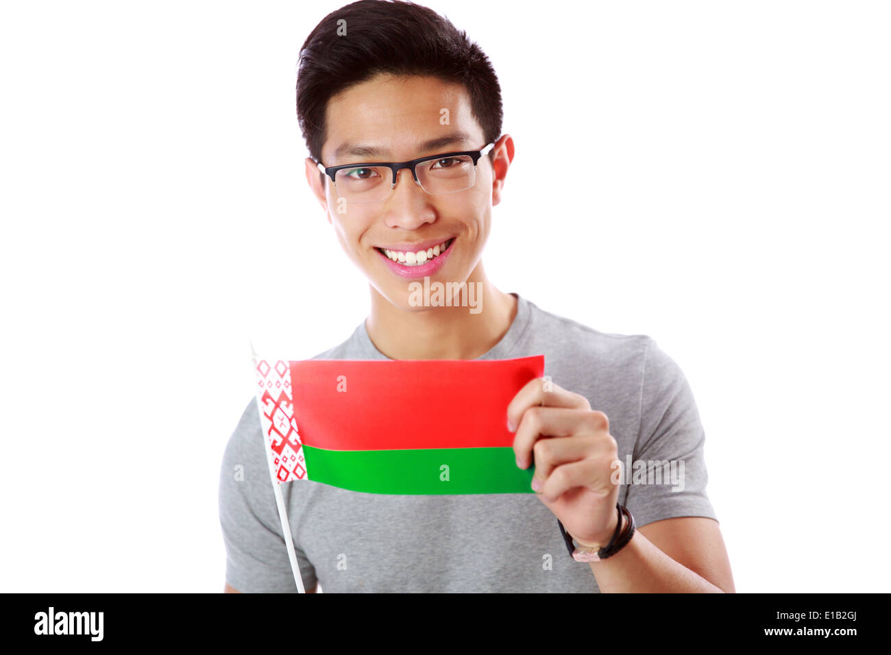 Happy young asian man holding flag of Belarus over white background ...