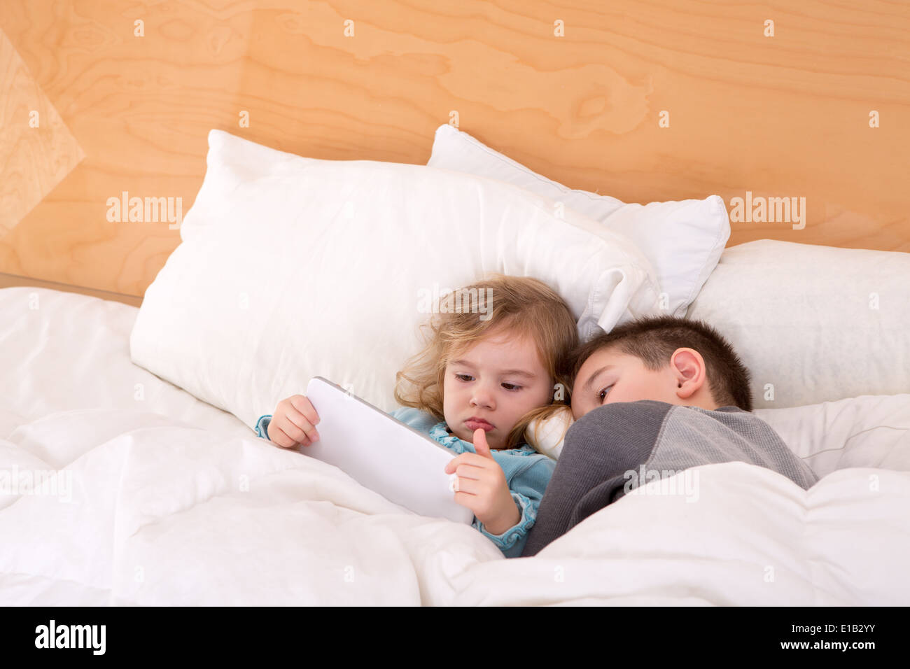 Tired little brother and sister snuggling up together in a warm ...