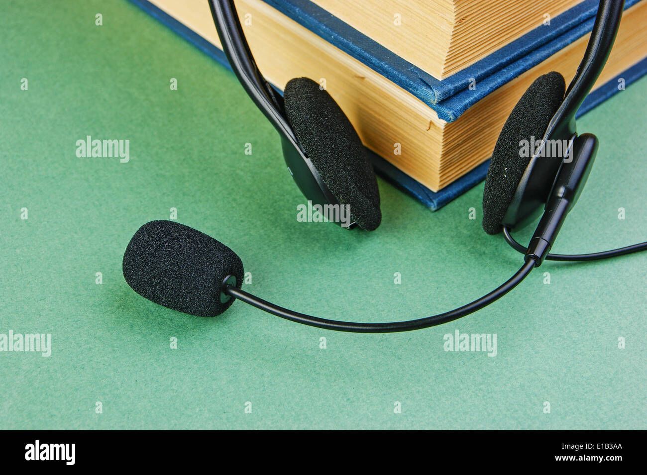 Headphones with a microphone and a stack of books on a green background ...