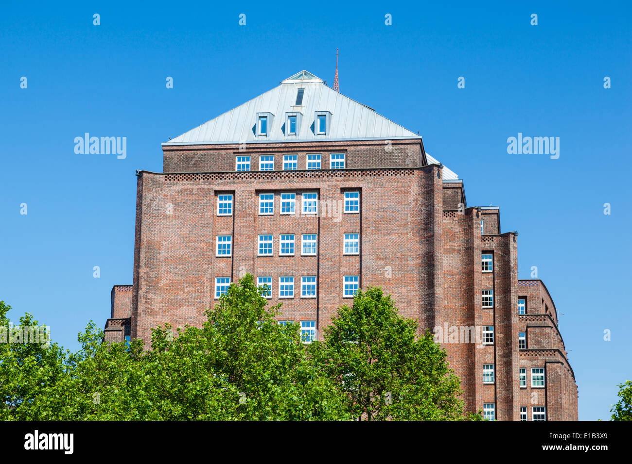 A harbor building in Hamburg, Germany behind some trees near the ...