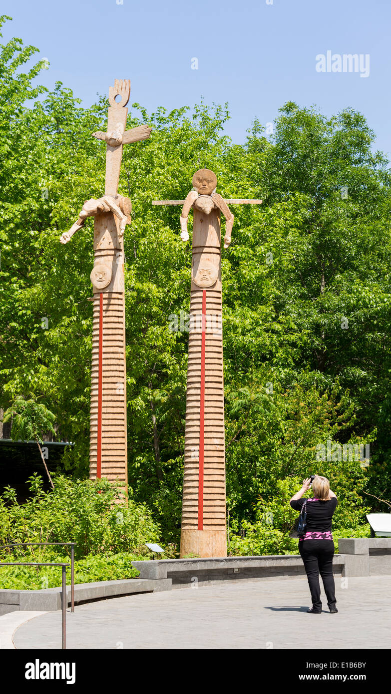 Woman tourist takes photo of totem poles sculpture called We Were ...