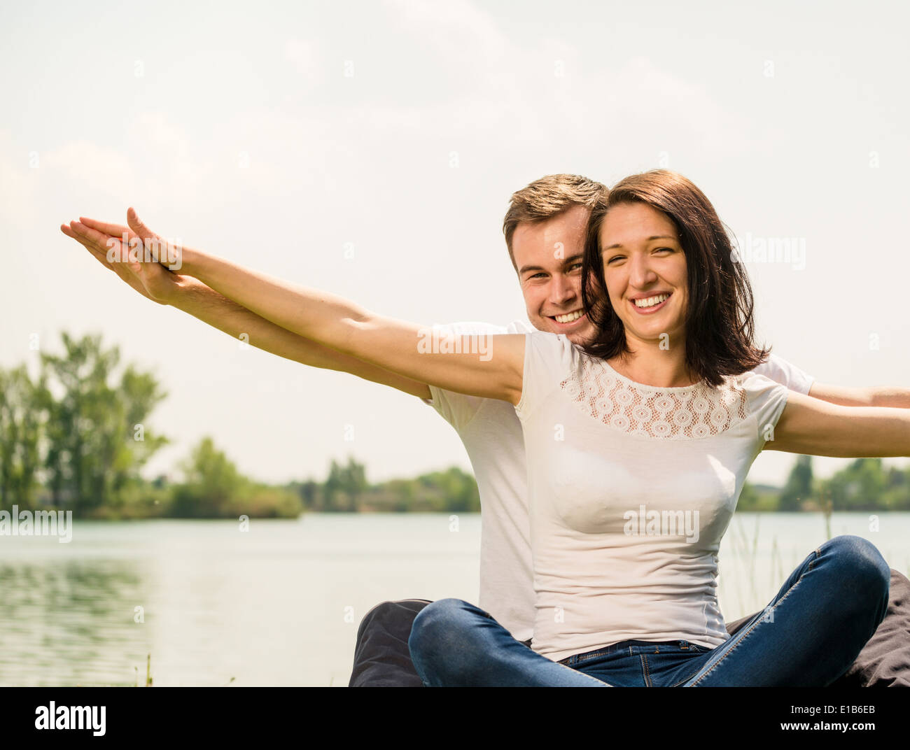 Young couple enjoy life together in nature - making airplane with hands ...
