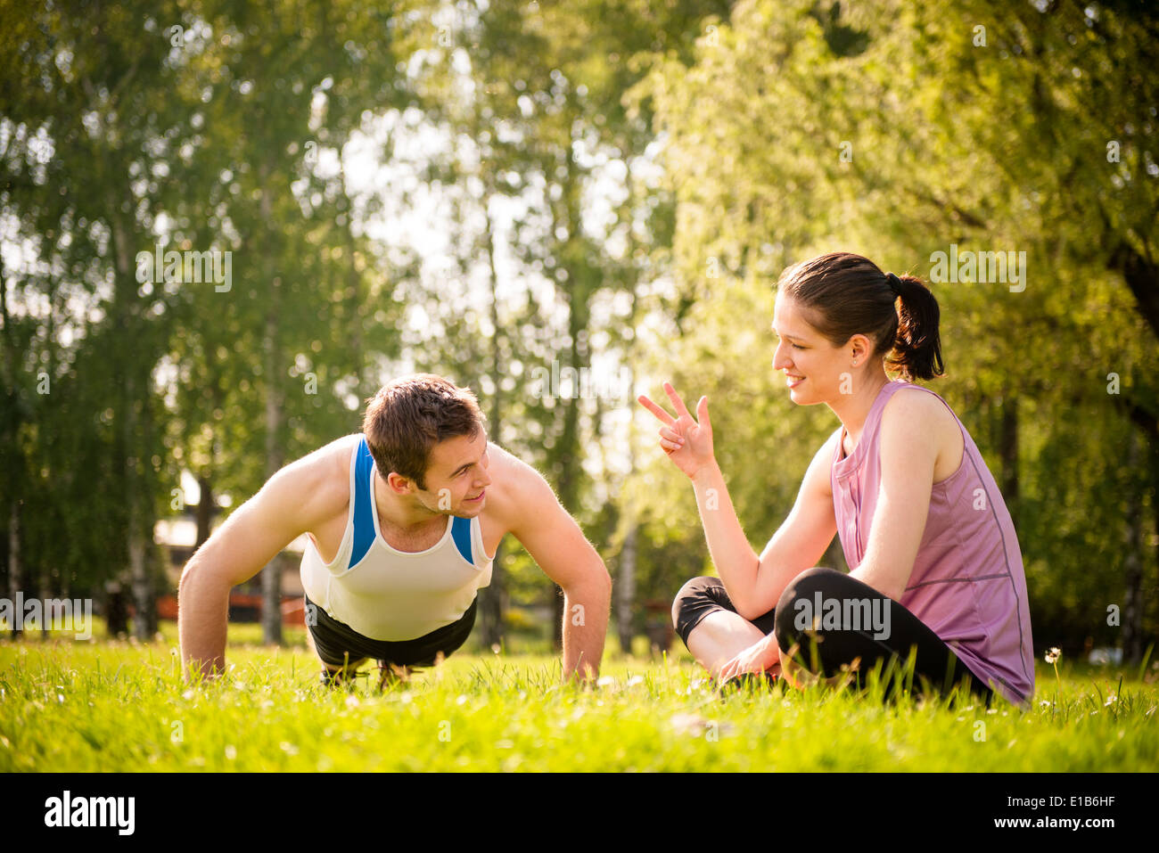 Man making push-ups while woman is counting their number - outdoor in ...