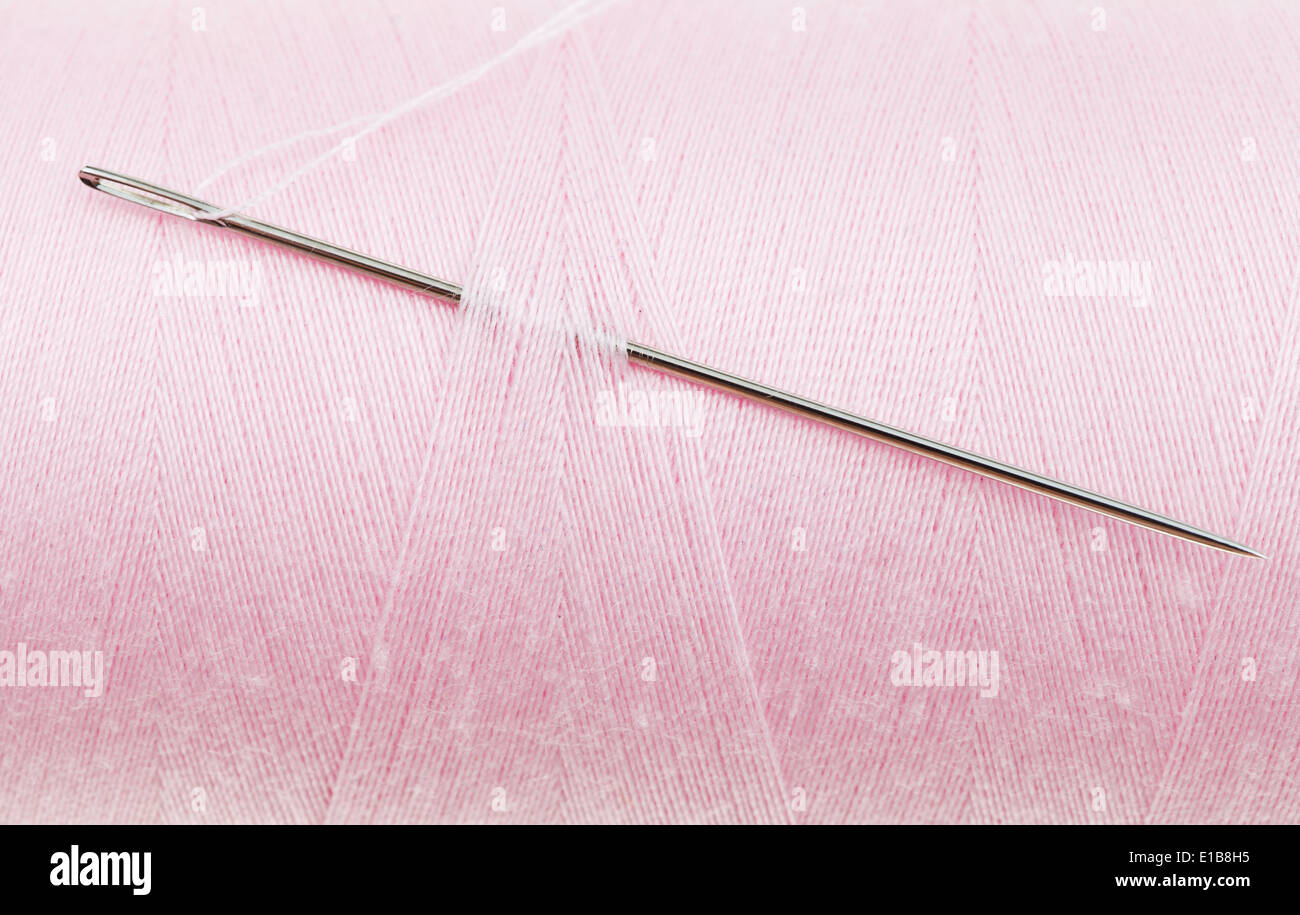 Hand sewing needle in pink thread bobbin close up Stock Photo - Alamy