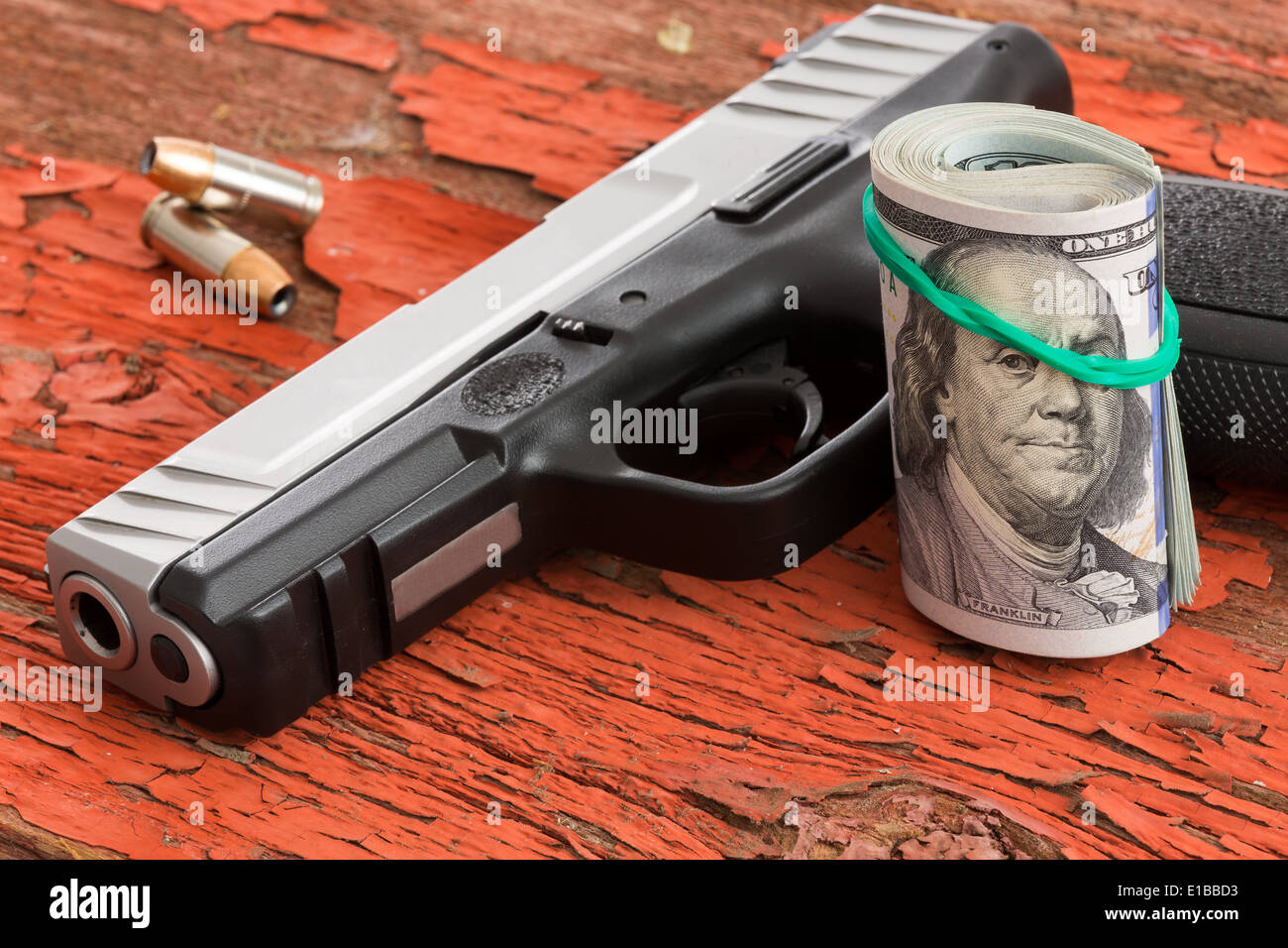 Gun with a roll of 100 dollar banknotes and two bullets lying on a ...