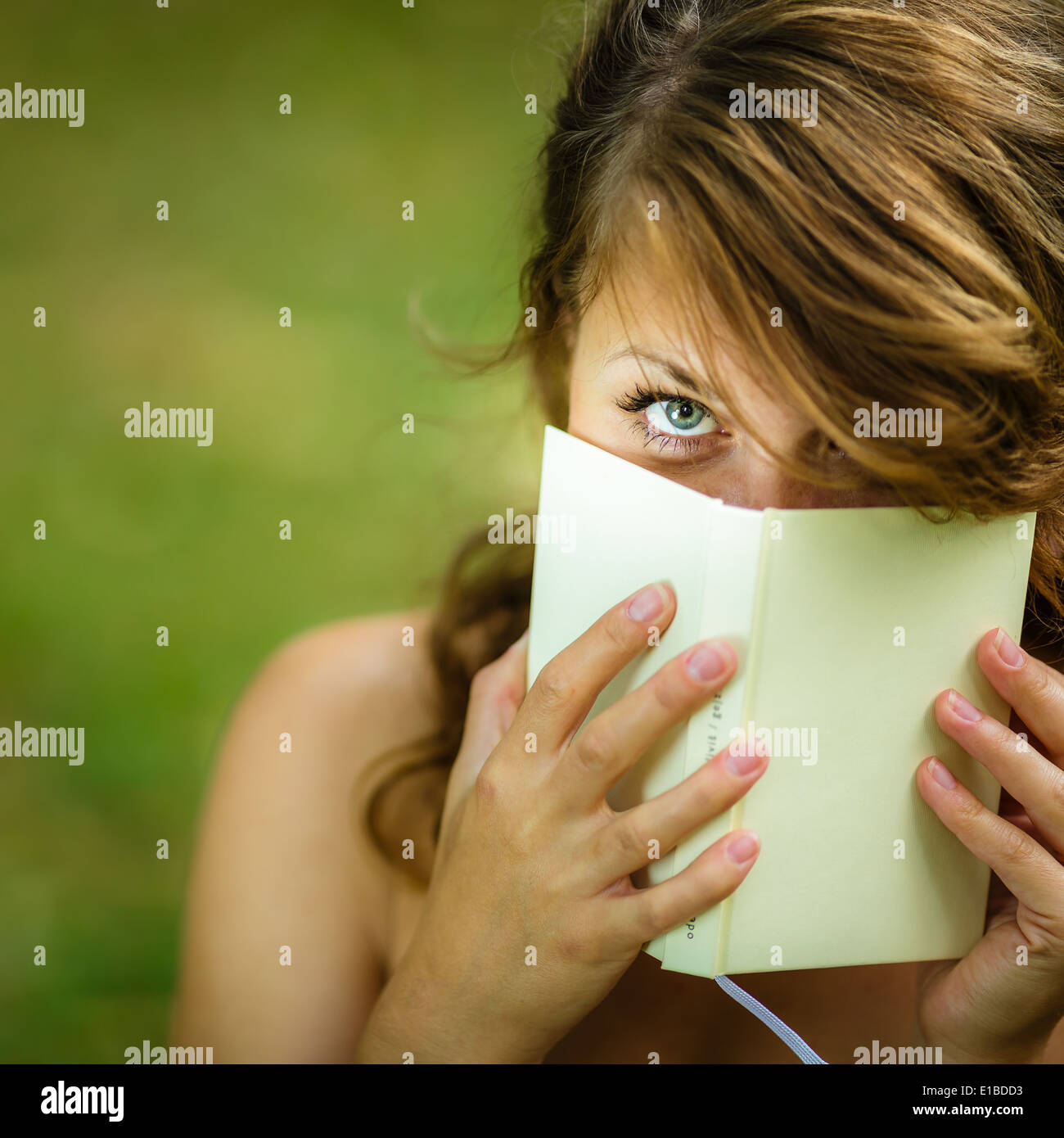 Cute young woman covering her face with a book she is reading Stock ...