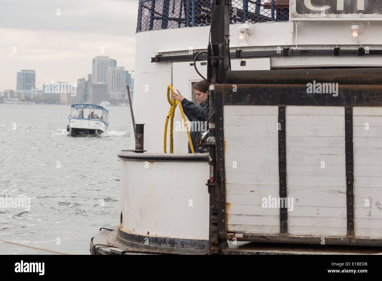Female ferry working prepares to throw rope to moor the ferry to the ...