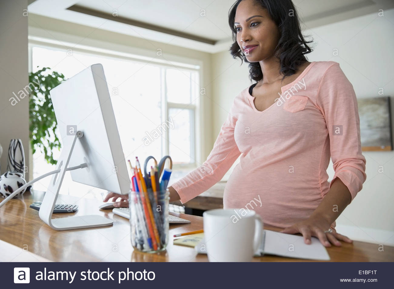 Pregnant woman using computer at home Stock Photo - Alamy
