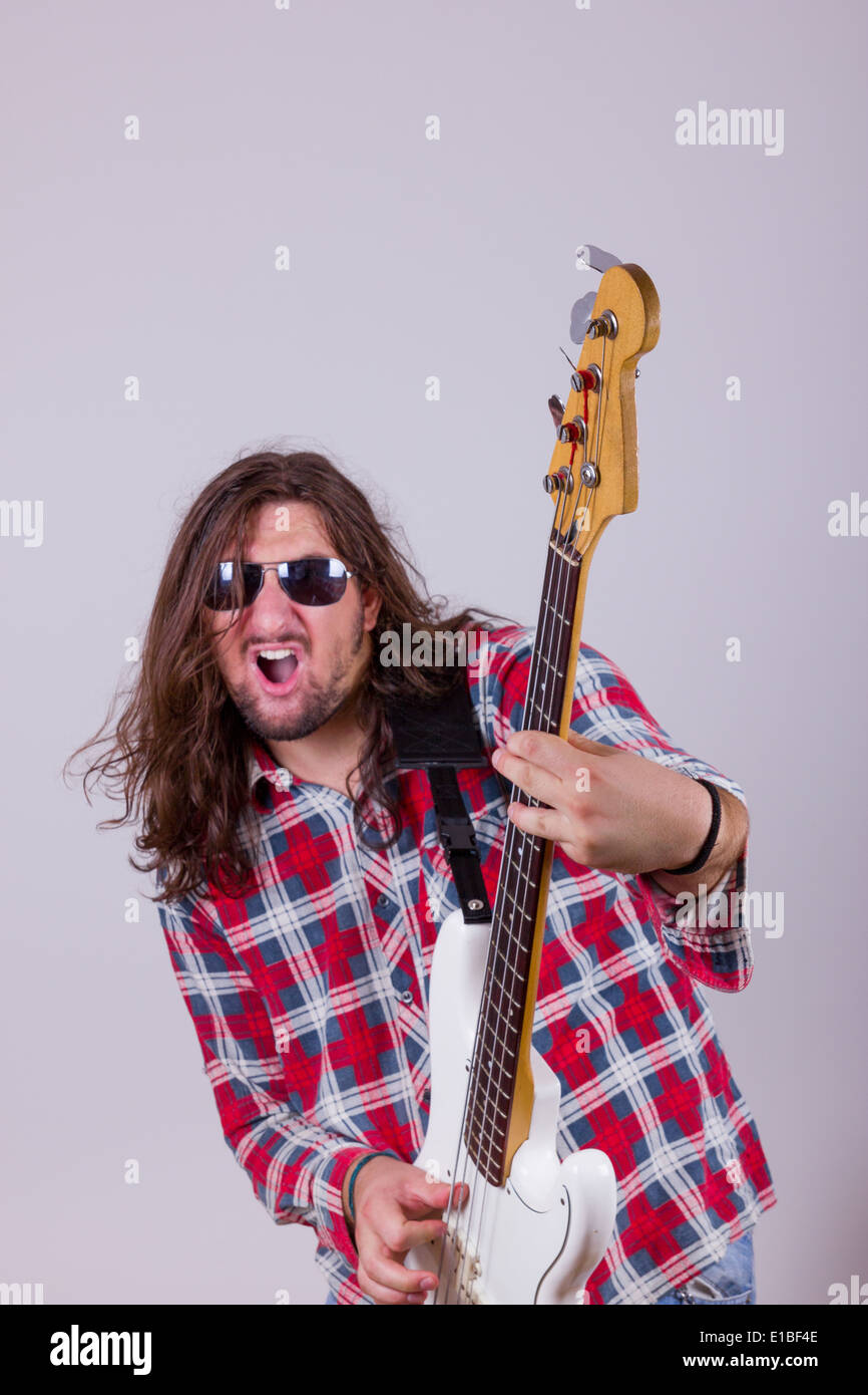 man with face expression playing electric bass guitar, isolated on gray ...