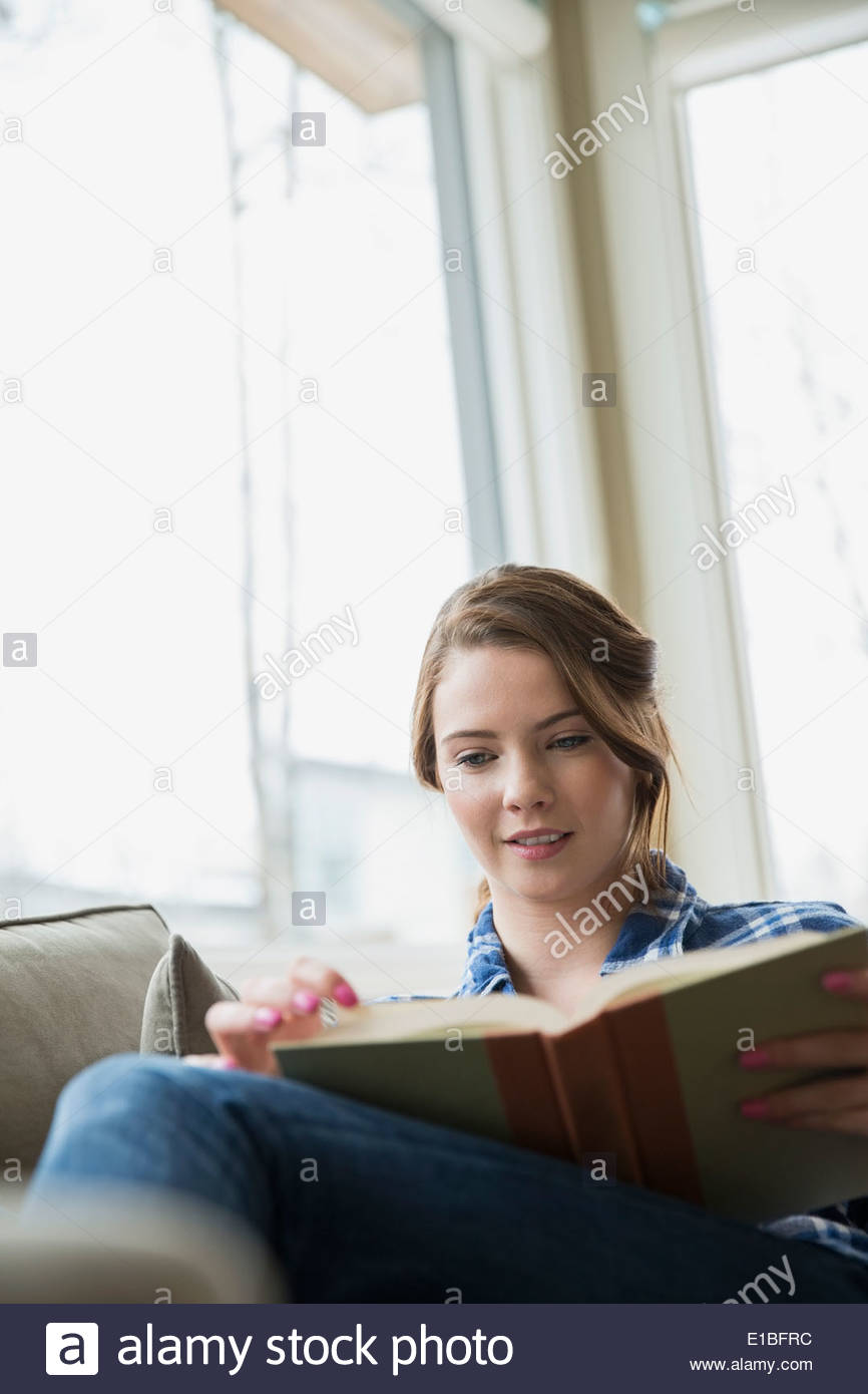 Woman reading book on sofa hi-res stock photography and images - Alamy